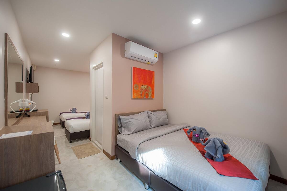 Quarto de hotel com cama, escrivaninha, cadeira, espelho, ar-condicionado e um quadro na parede.
