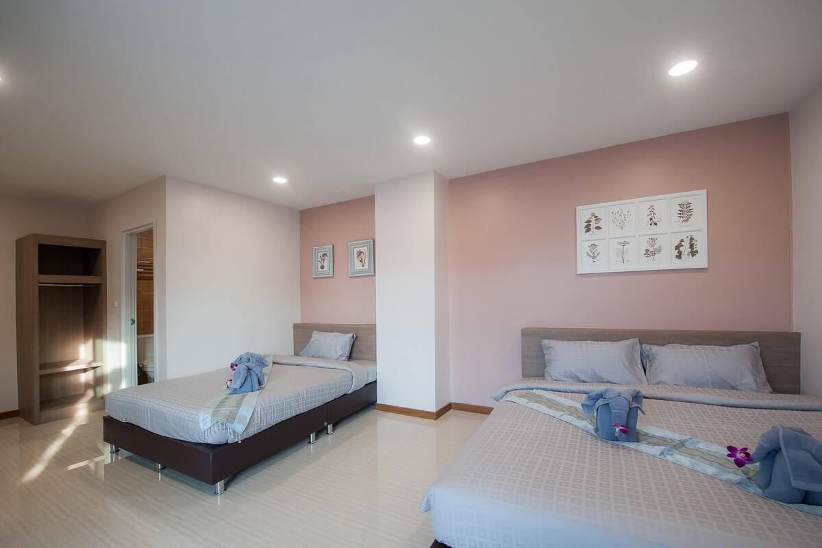 Quarto de hotel com duas camas, um guarda-roupa e uma parede decorada com quadros.
