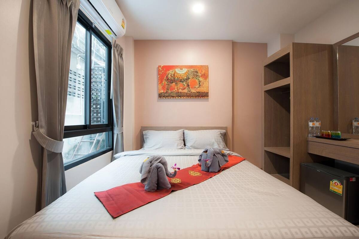 Quarto de hotel com cama, janela com cortinas, um quadro na parede e um guarda-roupa.