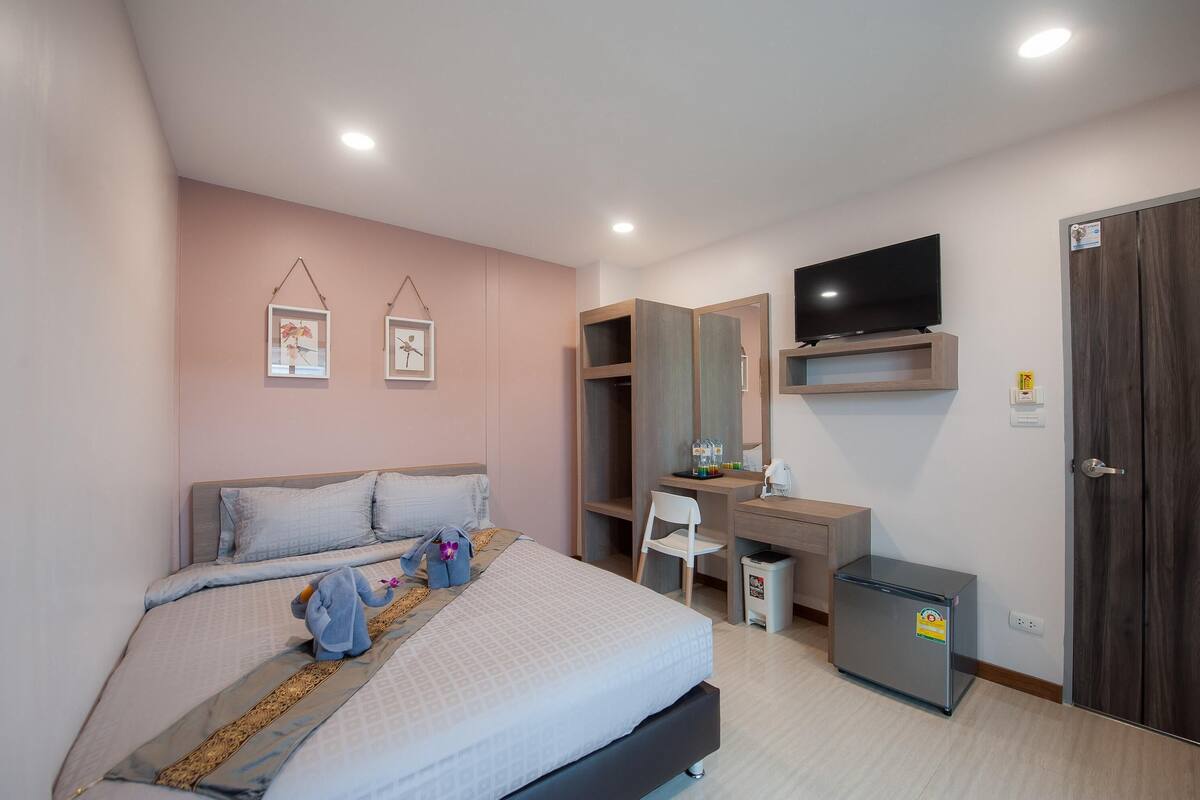 Quarto de hotel moderno com uma cama, uma mesa, uma televisão e um guarda-roupa.
