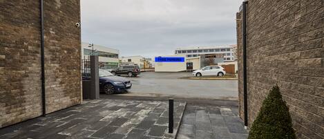 Uma área de estacionamento com um letreiro de 'Estacionamento Gratuito', paredes de tijolos e um caminho pavimentado.