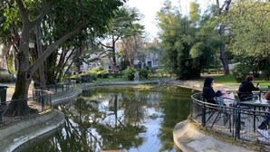 Um parque com lago, bancos e uma tampa de esgoto circular.