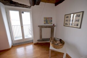 Quarto com piso de madeira, lareira, porta de varanda e um quadro na parede.