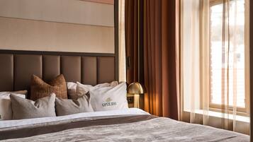 Quarto de hotel com uma cama grande, cabeceira e janela com cortinas.