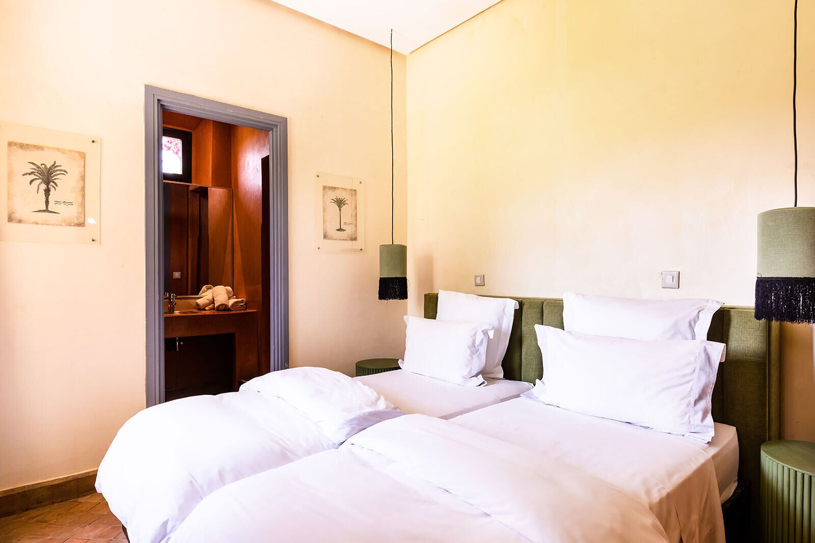 Quarto de hotel com uma cama, um guarda-roupa de madeira e duas luminárias fixadas na parede.