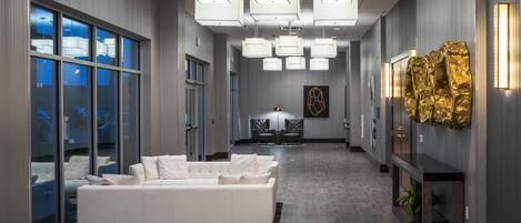 Um hall moderno com um sofá branco, luminárias pendentes e uma escultura dourada.