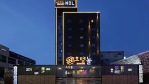 Um edifício de hotel moderno com um letreiro 'HOTEL NOL' bem visível no topo.