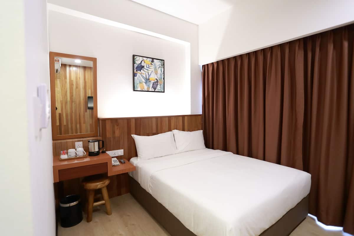 Quarto de hotel com secretária de madeira, uma cama, um quadro na parede e cortina marrom.