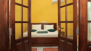 Quarto com cama, paredes amarelas e porta de madeira.