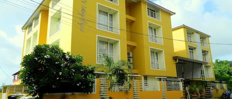 Um edifício amarelo de vários andares com varandas e uma placa com a inscrição 'Le Xinhai'.