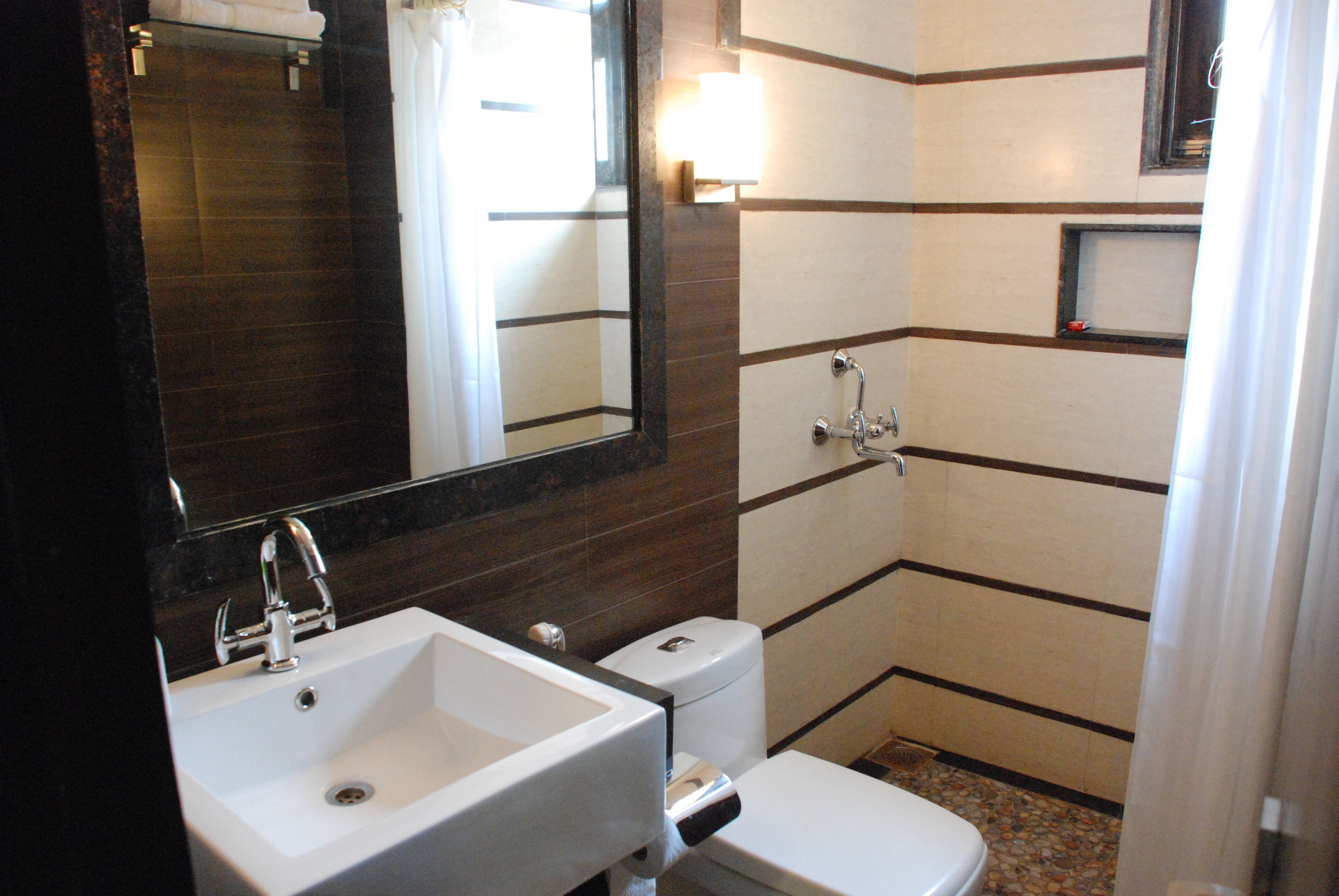 Casa de banho com lavatório branco, sanita e espelho.