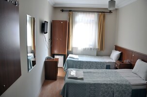 Quarto de hotel com duas camas, guarda-roupa, escrivaninha, cadeira, televisão e janela com cortinas.