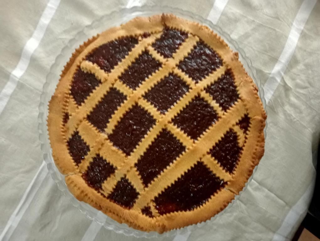 Uma torta com cobertura em treliça sobre um prato de vidro transparente.