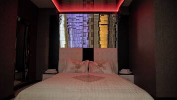 Quarto moderno com uma cama grande, cabeceira com design único e uma faixa de luz vermelha acima da cama.