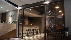 Uma área de recepção com balcão de check-in, espaço de estar com banquetas e uma escultura decorativa de peixe.