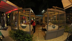 Restaurante com paredes de vidro, chão de azulejos e uma pessoa trabalhando no balcão.
