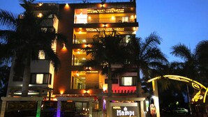 Um hotel com vários andares, letreiros iluminados e uma entrada imponente.