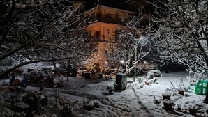 Uma área externa coberta de neve, com um edifício ao fundo.