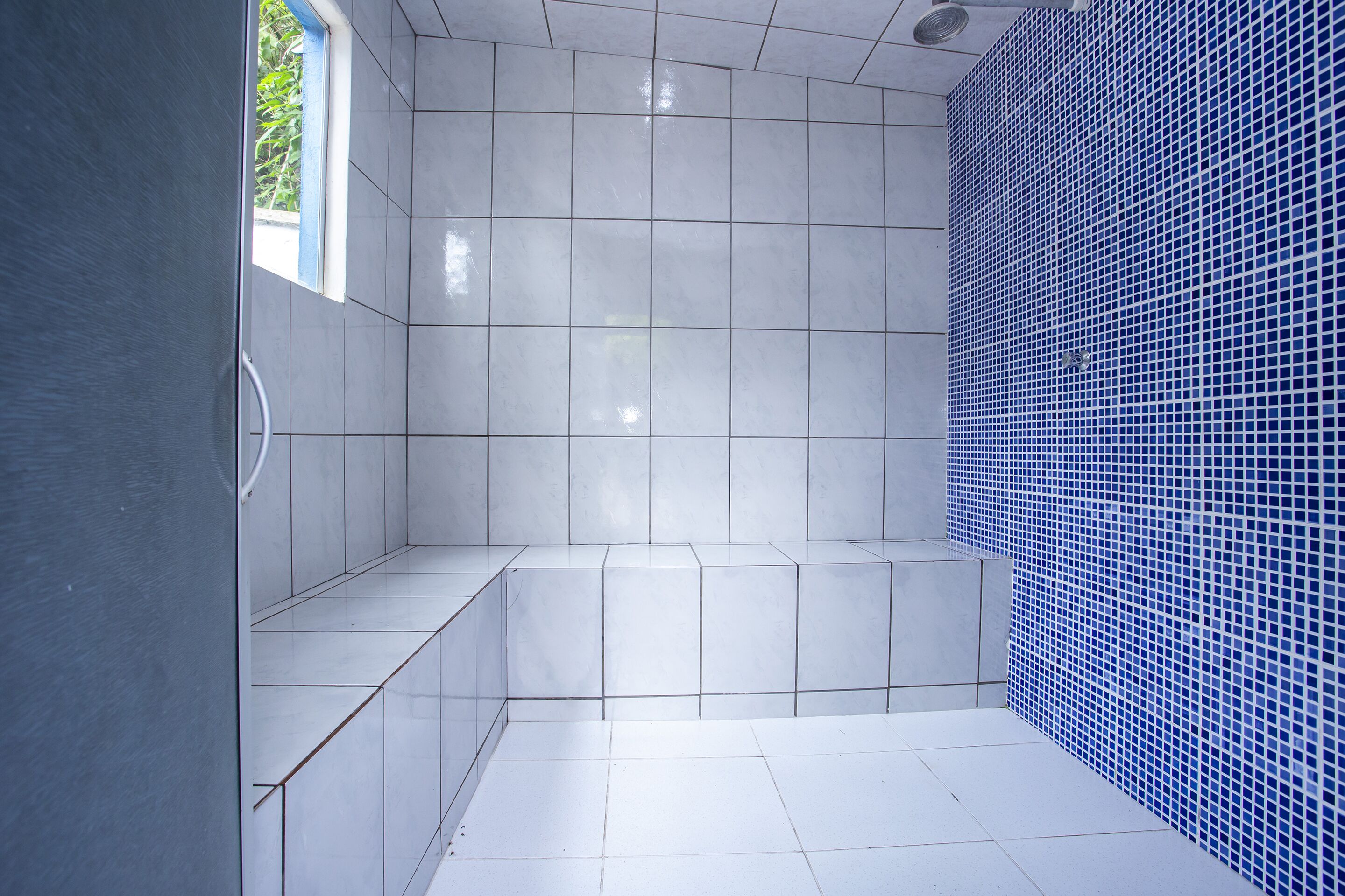 Casa de banho moderna com azulejos brancos e parede em mosaico azul.