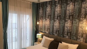 Quarto de hotel com cama, mesa de cabeceira, luminária e parede com padrão em mosaico.