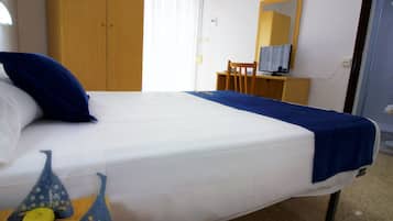Quarto de hotel com cama, escrivaninha, cadeira, espelho e janela com cortinas.