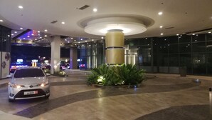Um edifício moderno com um elemento central circular, grandes janelas e um carro estacionado em frente.