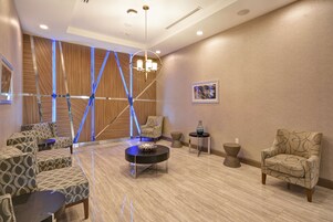 Uma área de estar moderna com sofás estampados, uma mesa de centro e um design de teto único com detalhes de iluminação azul.