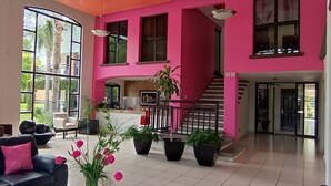 Um hall amplo com escada, janelas grandes e plantas em vasos.