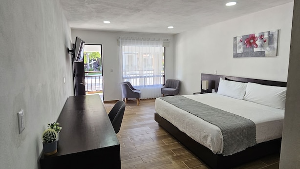 Quarto de hotel moderno com cama, secretária e cadeira.
