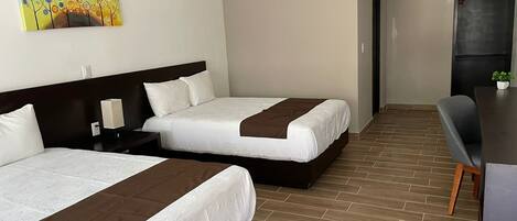 Quarto de hotel com duas camas, uma escrivaninha, uma cadeira e um quadro na parede.