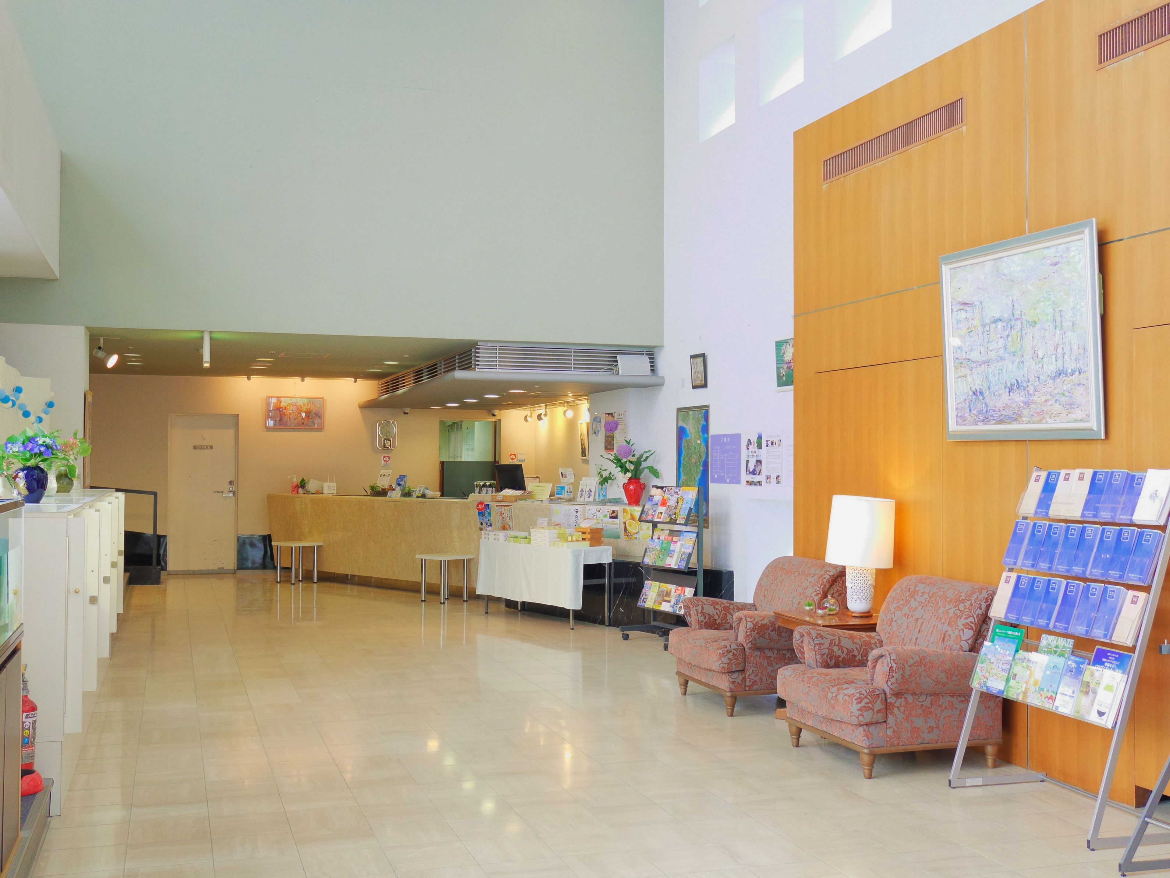 Um hall amplo com balcão de recepção, área de estar e painéis informativos.
