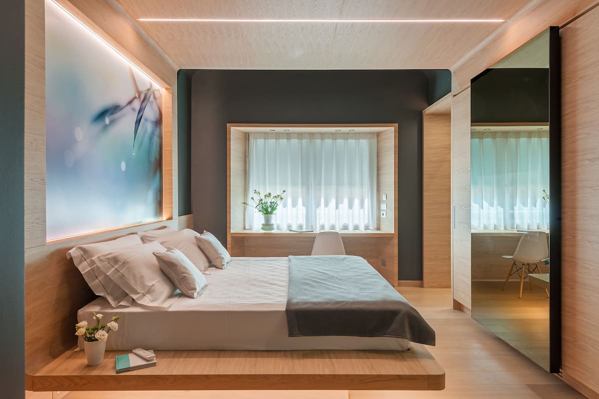 Um quarto moderno com cama, mesa de cabeceira e janela com cortinas.