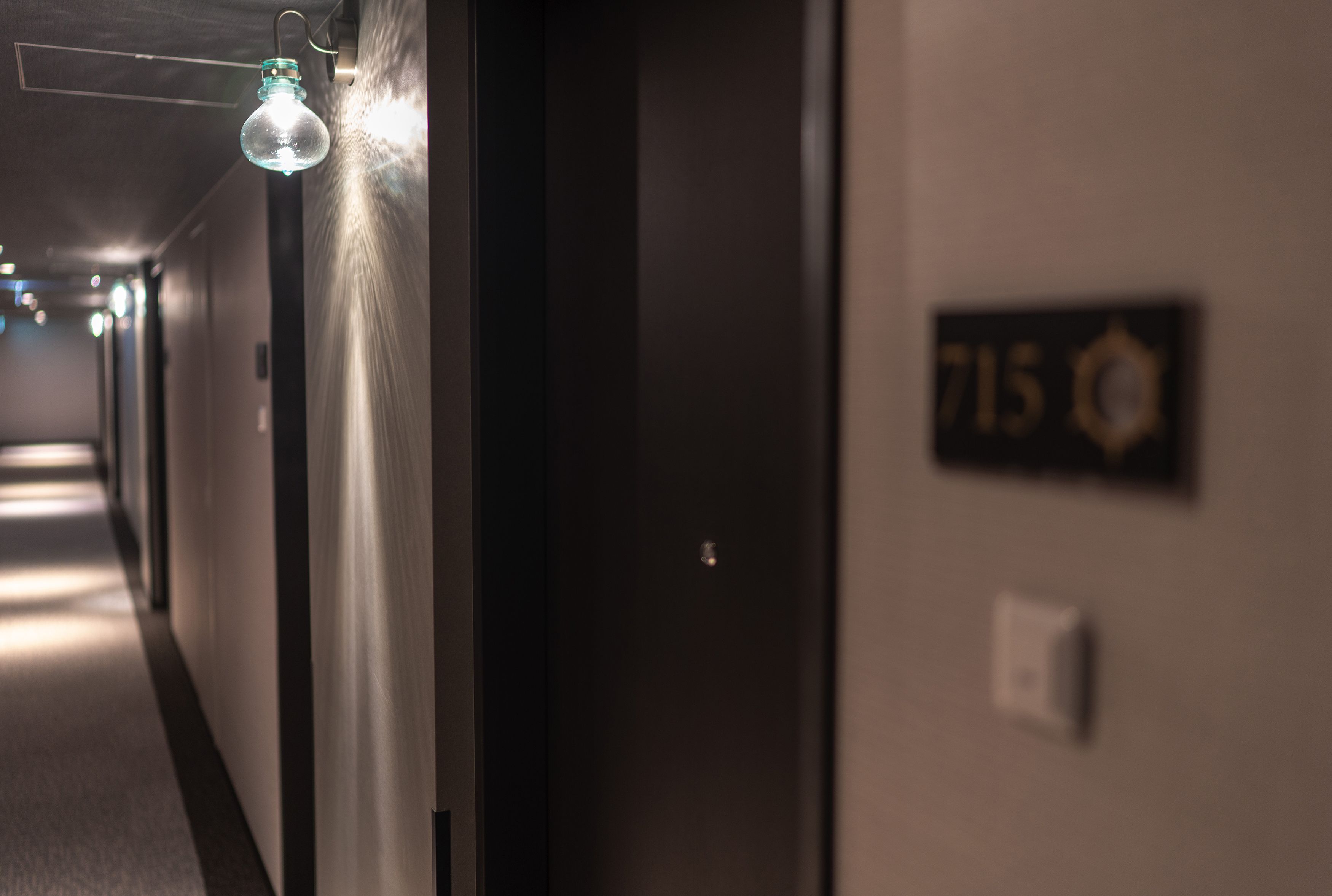 Corredor com luminária e porta com placa de número.