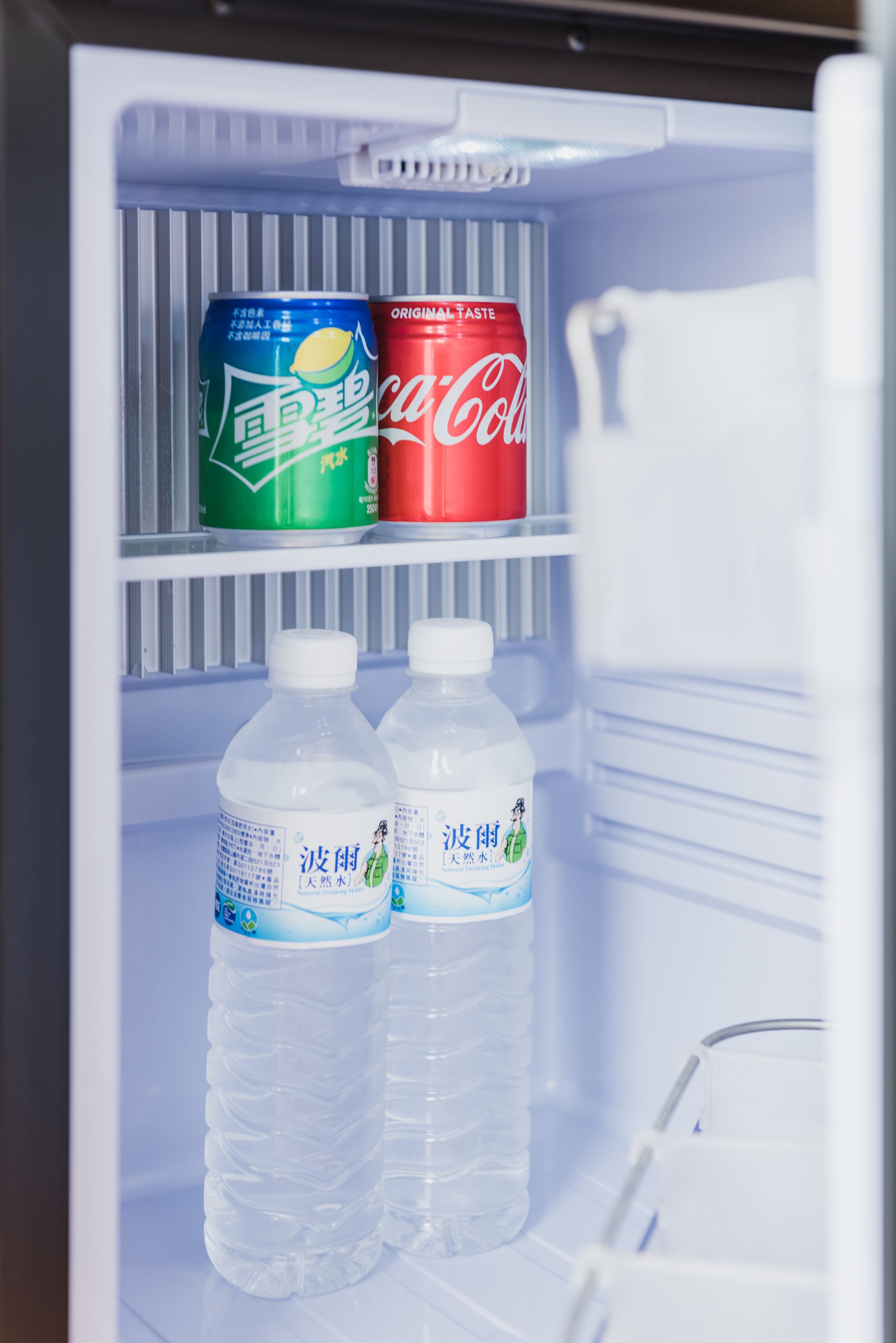 Um frigorífico com duas garrafas de água e duas latas de refrigerante.