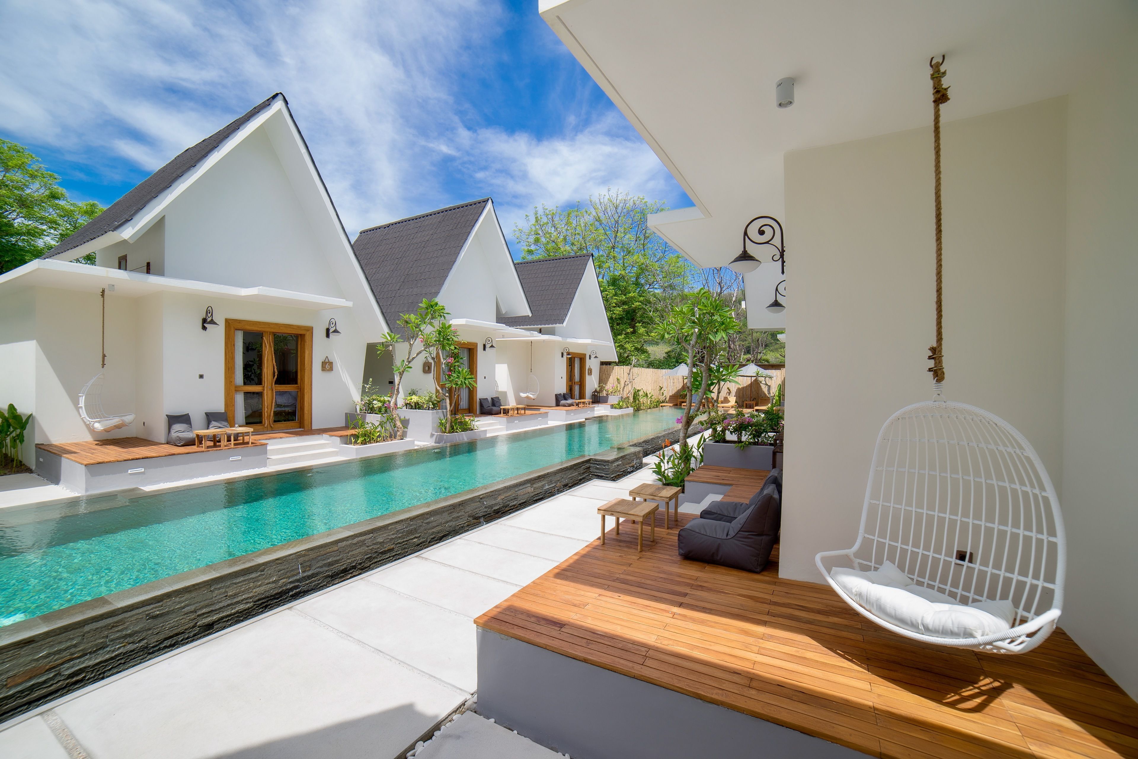 Um resort moderno com piscina, deck de madeira e paredes brancas.
