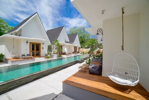 Um resort moderno com piscina, deck de madeira e paredes brancas.