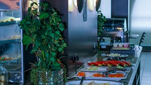 Buffet montado com diversos alimentos e uma planta decorativa.
