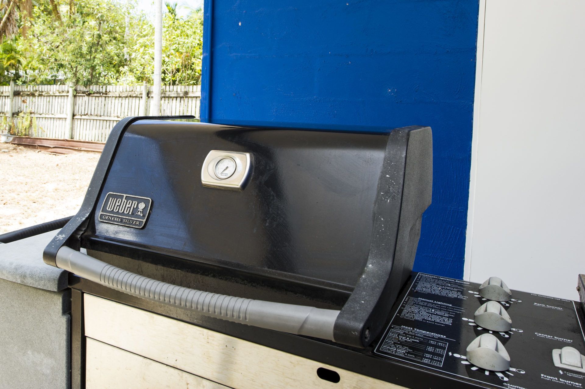 Uma churrasqueira Weber Genesis Silver com termômetro digital e botões de controle.