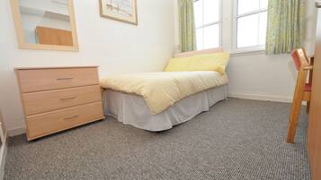 Quarto com cama, penteadeira, espelho e janela com cortinas.