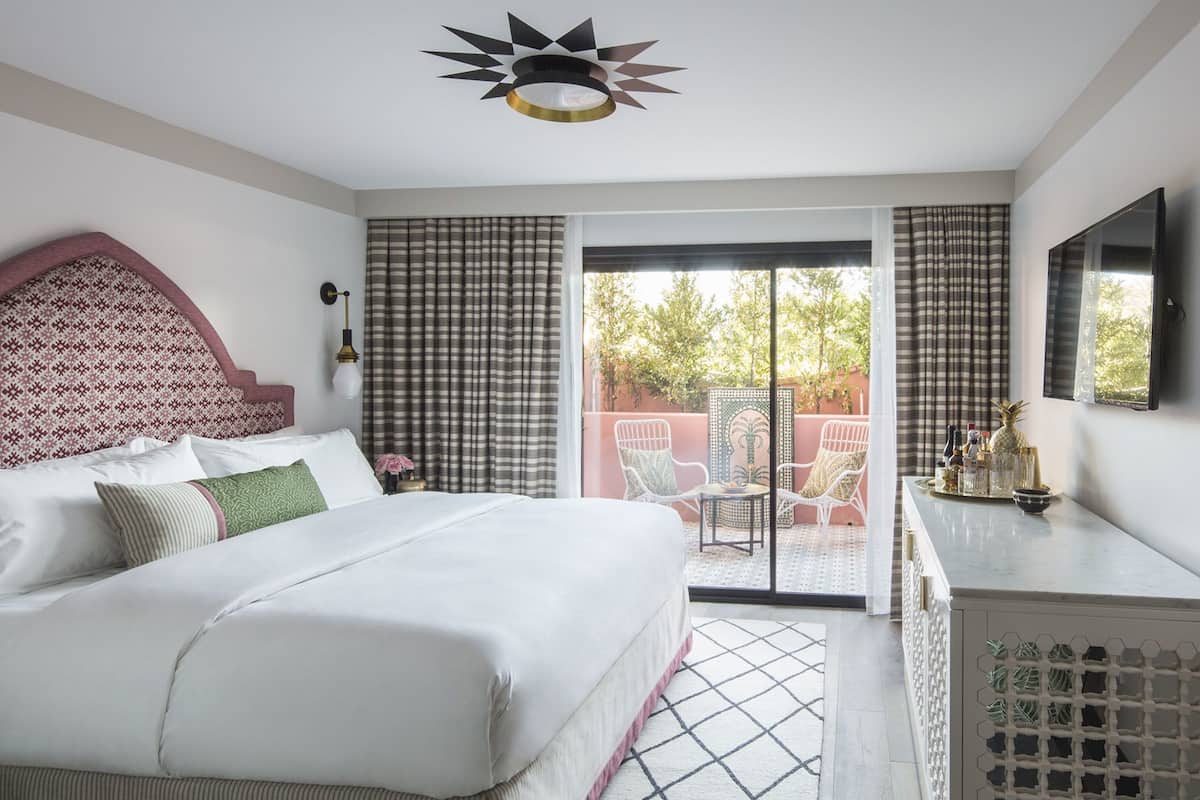 Quarto de hotel com uma cama, uma escrivaninha, uma cadeira e vista para o exterior.
