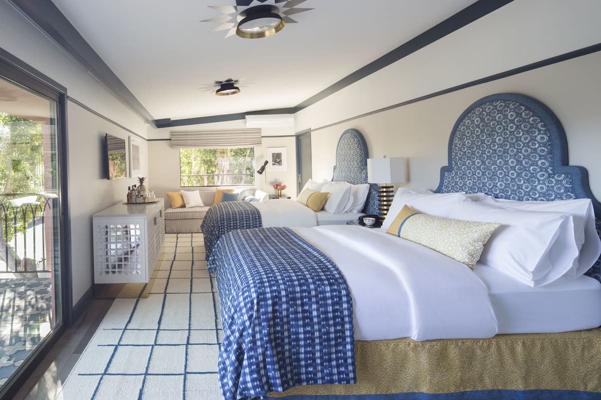Quarto de hotel moderno com uma cama grande,  área de estar com vista e varanda.