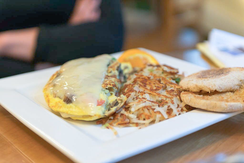 Um prato com omelete, hash browns e torradas.