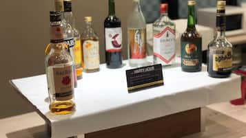 Vários garrafas de bebidas alcoólicas sobre uma mesa, com um aviso que diz 'Happy Hour'.