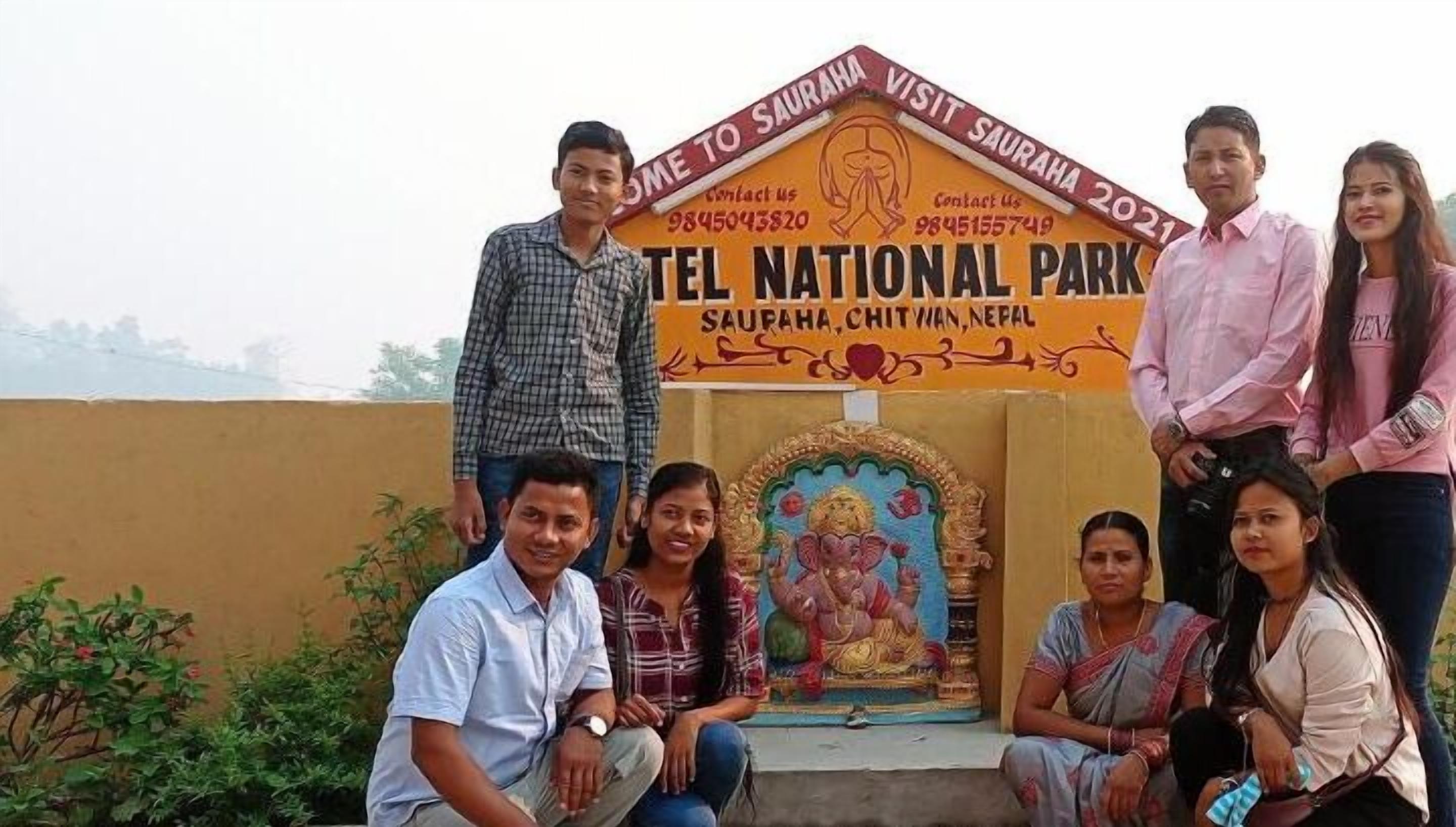 Um grupo de pessoas em frente a uma placa do Hotel National Park, indicando ser um lugar para visitar.