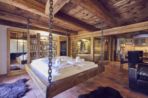 Um quarto espaçoso com cama de dossel, teto de madeira e banheiro à vista, com pia e espelho.