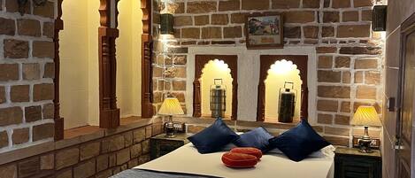 Quarto com uma cama grande, um candelabro e arandelas decorativas.