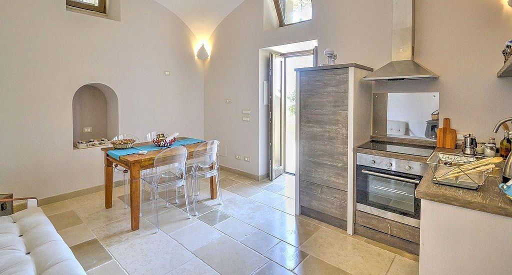 Uma cozinha moderna com forno embutido e um espaço de refeições com mesa e cadeiras.