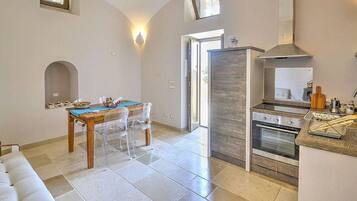 Uma cozinha moderna com forno embutido e um espaço de refeições com mesa e cadeiras.