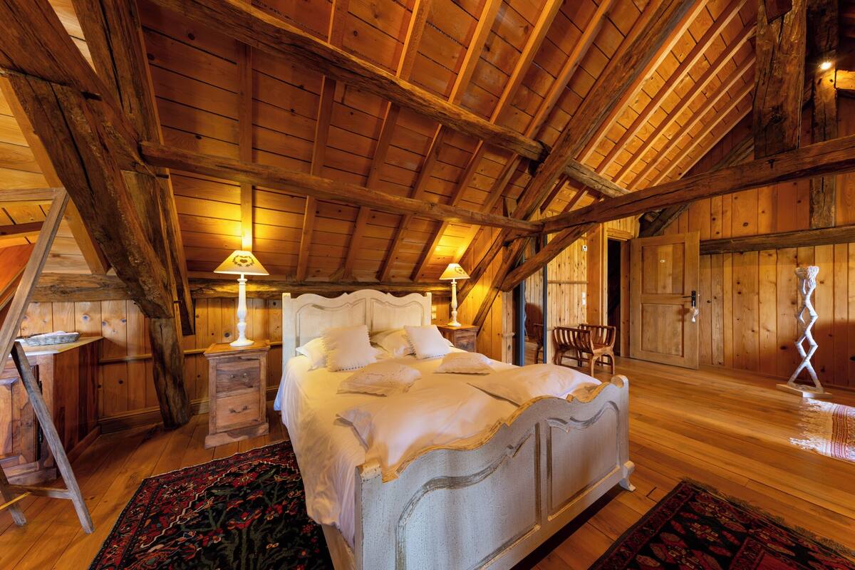 Um quarto de madeira com uma cama, duas mesas de cabeceira, um penteado e uma cadeira.