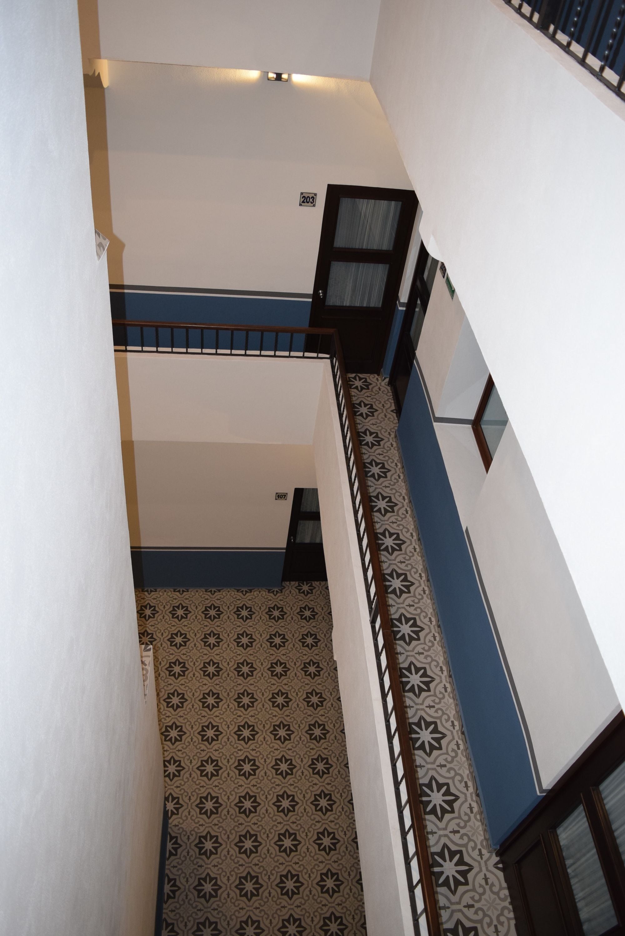 Interior com vários níveis, piso estampado, escada e corrimão.